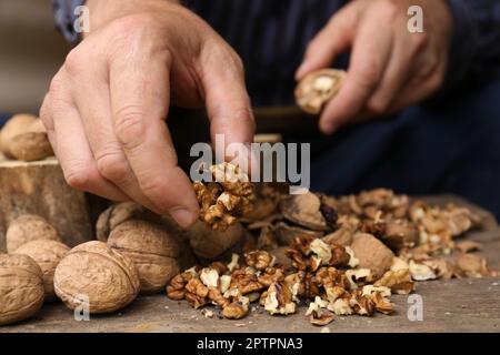 Man cracking walnuts at wooden table, closeup Stock Photo - Alamy