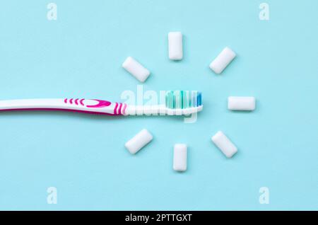Toothbrush and chewing gums lie on a pastel pink background. Top view ...