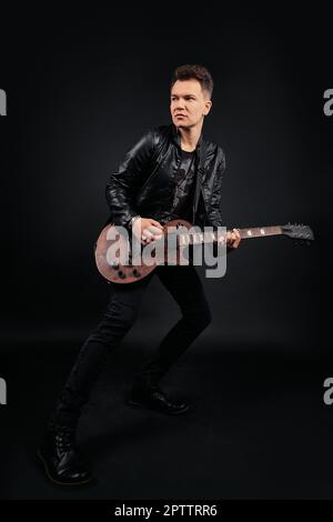 Brutal rocker playing electro guitar and dancing Stock Photo - Alamy