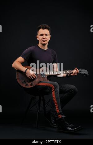 Low key portrait of man singing and playing electro guitar Stock Photo ...