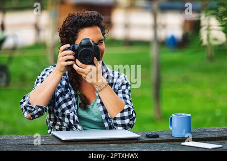 Human photographer works on her shoot in the countryside, outdoors. She ...