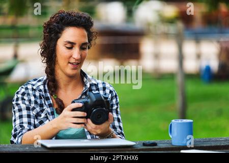 Human photographer works on her shoot in the countryside, outdoors. She ...