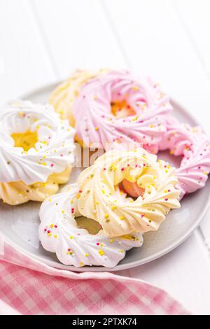 Different colors meringues with sprinkles on the plate Stock Photo - Alamy