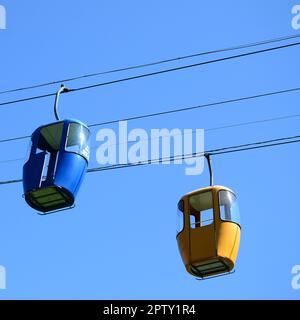 Blue and yellow passenger cable way cabins in the clear blue sky. Blue ...