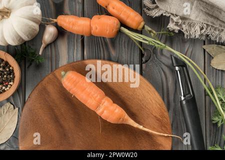 Peeling ripe orange carrot with vegetable peeler. Flat lay view. Fresh ...