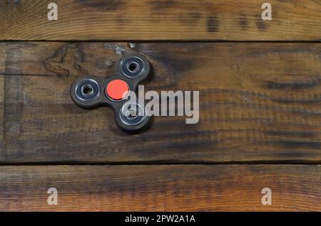 A rare handmade wooden fidget spinner lies on a brown wooden background ...