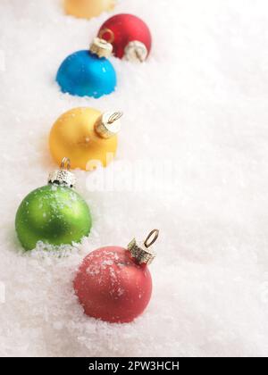 Colorful vintage Christmas baubles in the snow, wooden background with ...