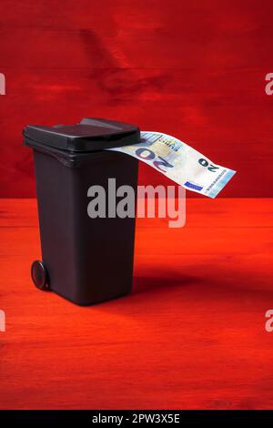 Euro banknote in a garbage can as a symbol for garbage fees, waste of ...