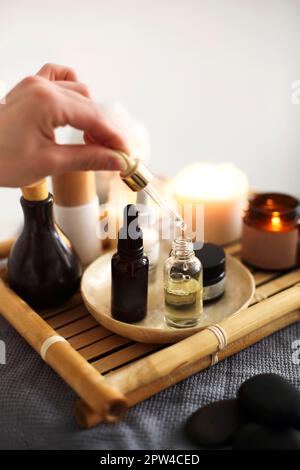 Crop masseuse using pipette with massage oil placed on tray with ...