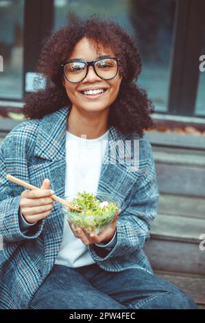 Positive african american girl in santa hat and sweater holding present ...