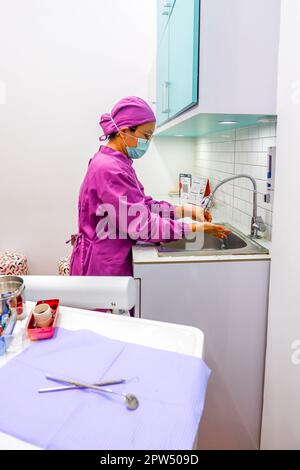 A female Asian dentist washing her hands before/after treating her ...