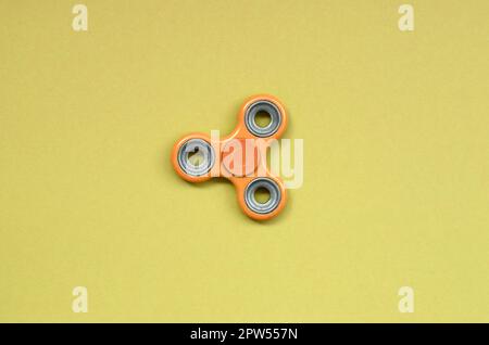 orange fidget spinner lies on texture background of fashion pastel ...
