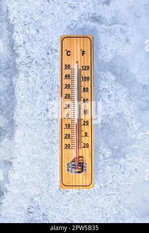 Thermometer laying on ice, showing minus 5 degrees. Sun shining from ...