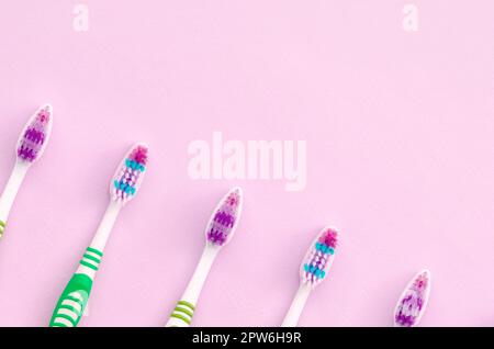 A lot of toothbrushes lie on a pastel pink background. Top view, flat ...