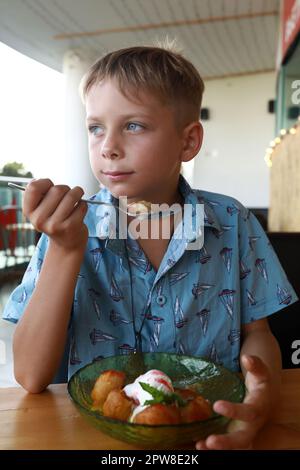 Child eating fried battered bananas in restaurant Stock Photo - Alamy