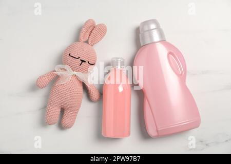 Bottles of laundry detergents and rabbit toy on light grey table, flat ...