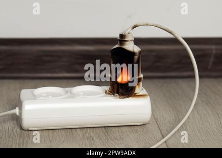 Inflamed plug in power strip indoors on wooden table. Electrical short ...