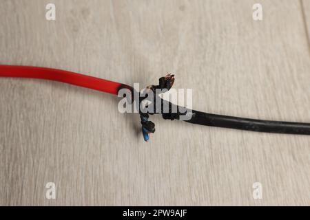 Burnt red wire on wooden floor, closeup. Electrical short circuit Stock ...