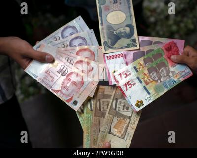 Asian child holding Indonesian rupiah, Singapore dollar, Saudi Arabia ...
