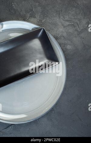 Black plate on tray with cutlery in brown napkin on grunge beige ...