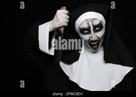 Scary devilish nun with knife on black background, space for text ...