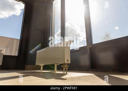 Vertically installed central heating radiator on the floor at the fully ...