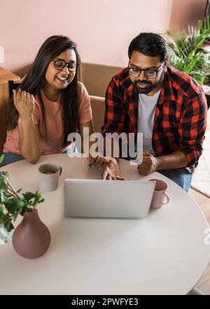 Happy indian family couple cuddle at desk make video call to friends ...