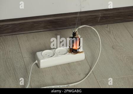 Inflamed plug in power strip indoors. Electrical short circuit Stock ...