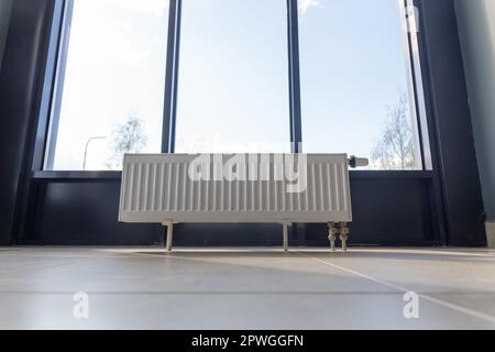 Vertically installed central heating radiator on the floor at the fully ...
