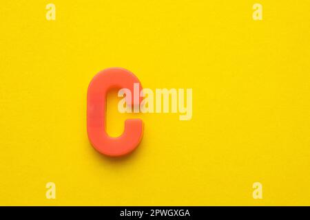 Peach colored plastic letter A uppercase on yellow foamy background ...
