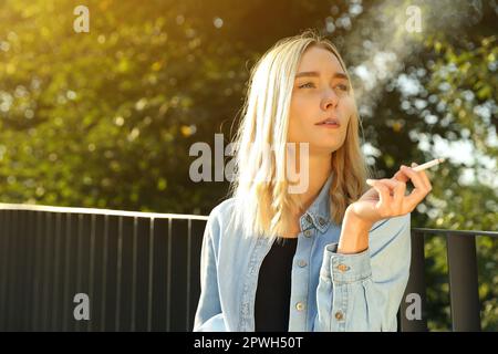 Woman smoking cigarette near railing outdoors. Space for text Stock ...