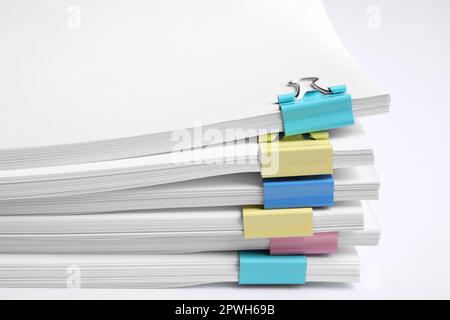 Many sheets of paper with colorful clips on white background, top view ...