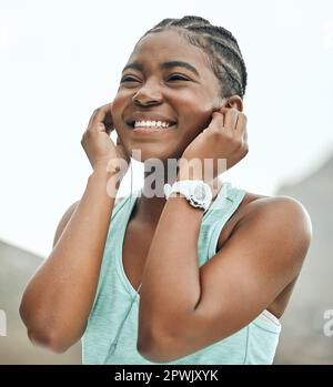 Music makes me feel great. a young woman listening to music while on a ...