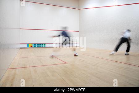 Squash players in action on a squash court (motion blurred image; color ...