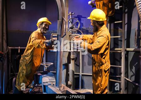 A group of oil rig, derick, well workers in orange jumpsuits, busy ...