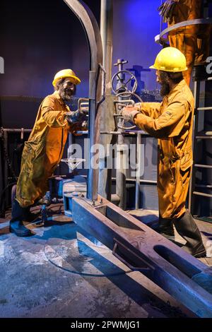 A group of oil rig, derick, well workers in orange jumpsuits, busy ...