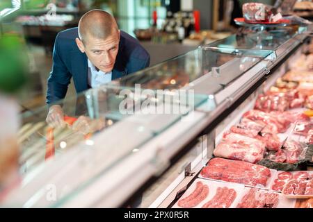 Focused man examines the production in the department of the butcher ...