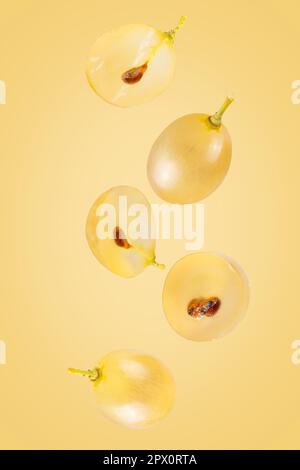 Isolated flying grapes. Five whole and sliced grape fruits falling on ...