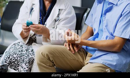 Elderly physician taking patient insulin level test using glucometer in ...