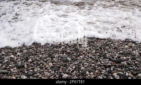 The edge of the sea, views along a pebbled beach as waves reach the ...