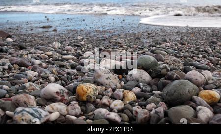 The edge of the sea, views along a pebbled beach as waves reach the ...