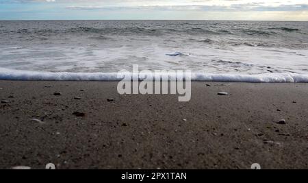 The edge of the sea, views along a pebbled beach as waves reach the ...