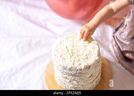 Hand of the little girl is smashing a beautiful delicious cake for ...