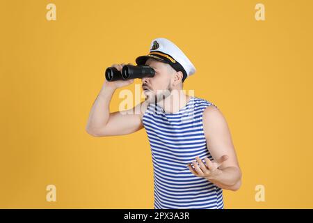 Sailor looking through binoculars on light blue background Stock Photo ...