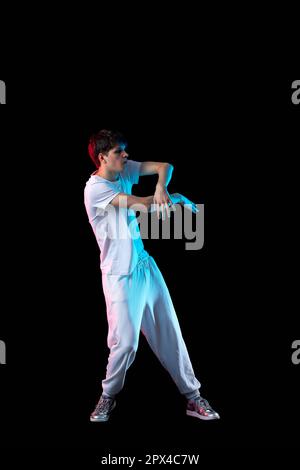 young clubber man in white t-shirt dancing in neon light on black ...