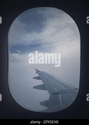 Plane flight through the dense foggy clouds. Airplane wing seen through ...
