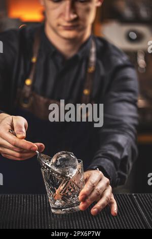Barman putting ice ball into old fashioned glass Stock Photo - Alamy