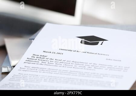 Acceptance letter from university, books and laptop on wooden table ...