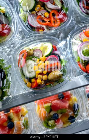 Plastic boxes with pre-packaged vegetable salads, put up for sale in a ...