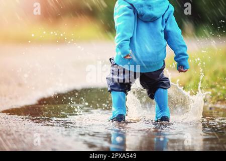 Small child jumping through puddles in nature in spring Stock Photo - Alamy